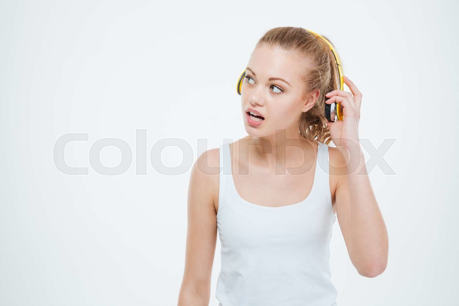 Thoughtful Curious Young Woman Taking Off Yellow Headphones Stock