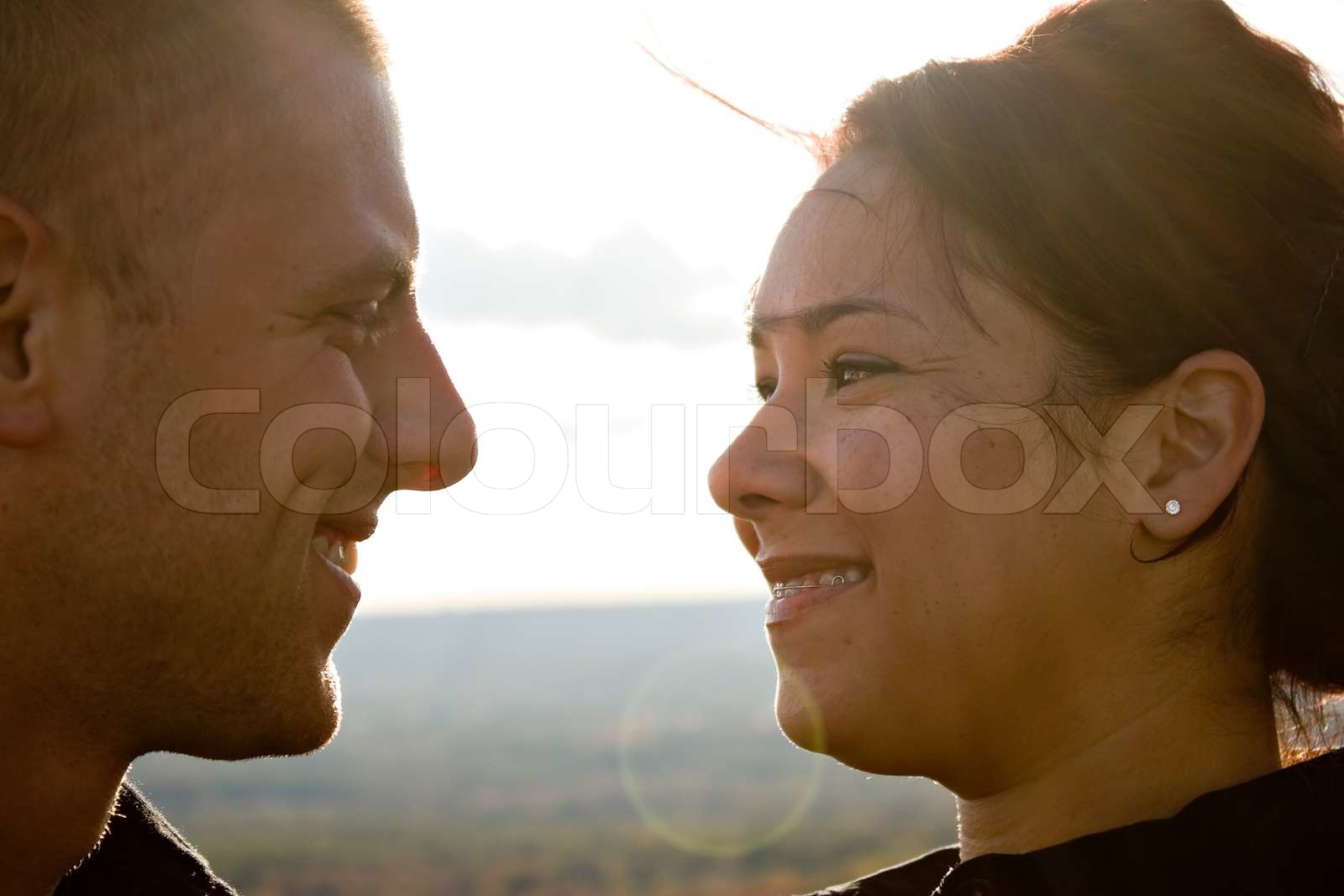 A Young Happy Couple Gazing Into Each Others Eyes Outdoors On A Sunny