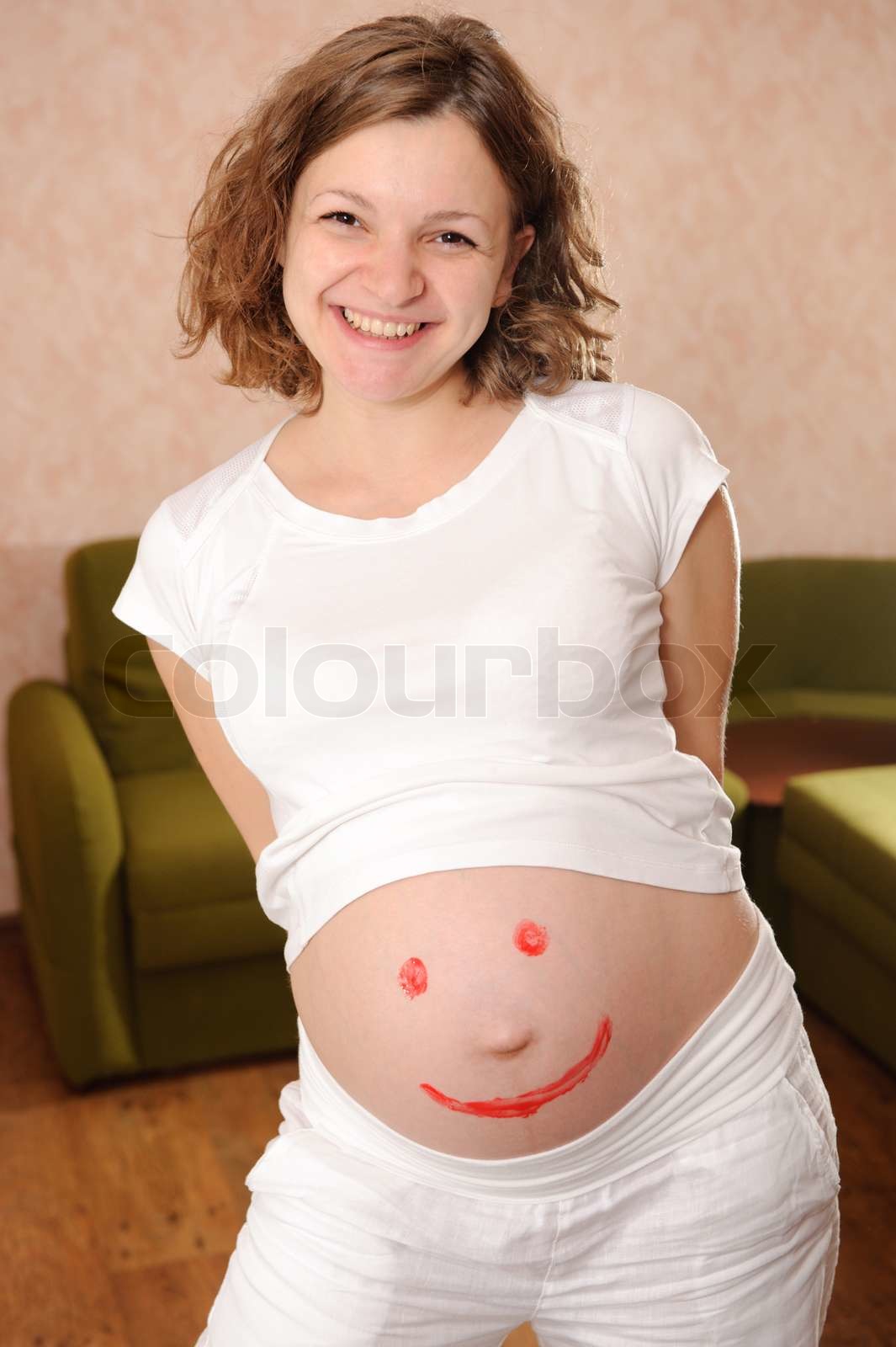 Young Pregnant Standing With Smile Sign Painted On Belly Stock Image