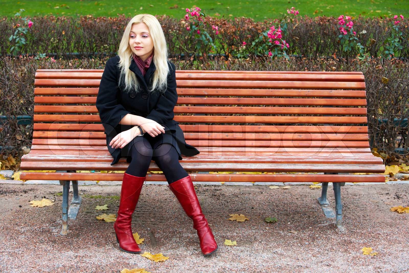 Young Woman Sitting Alone On Bench In Park Looking Down Stock Image