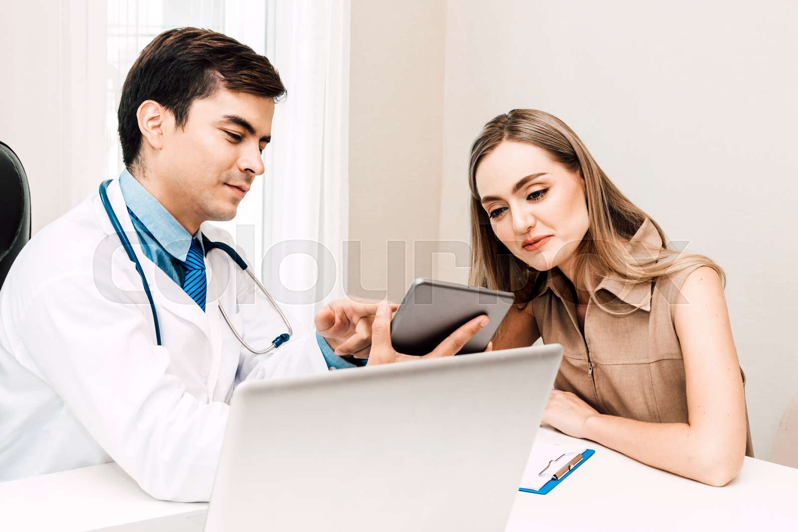 Doctor Discussing And Consulting With Female Patien On Doctors Table In