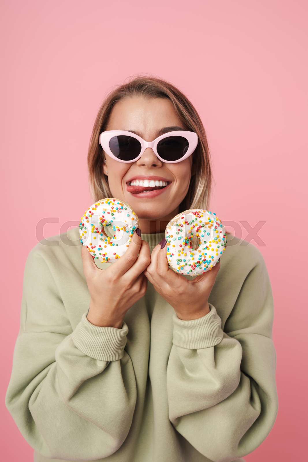 Portrait Of Amusing Woman Holding Donuts And Sticking Out Her Tongue
