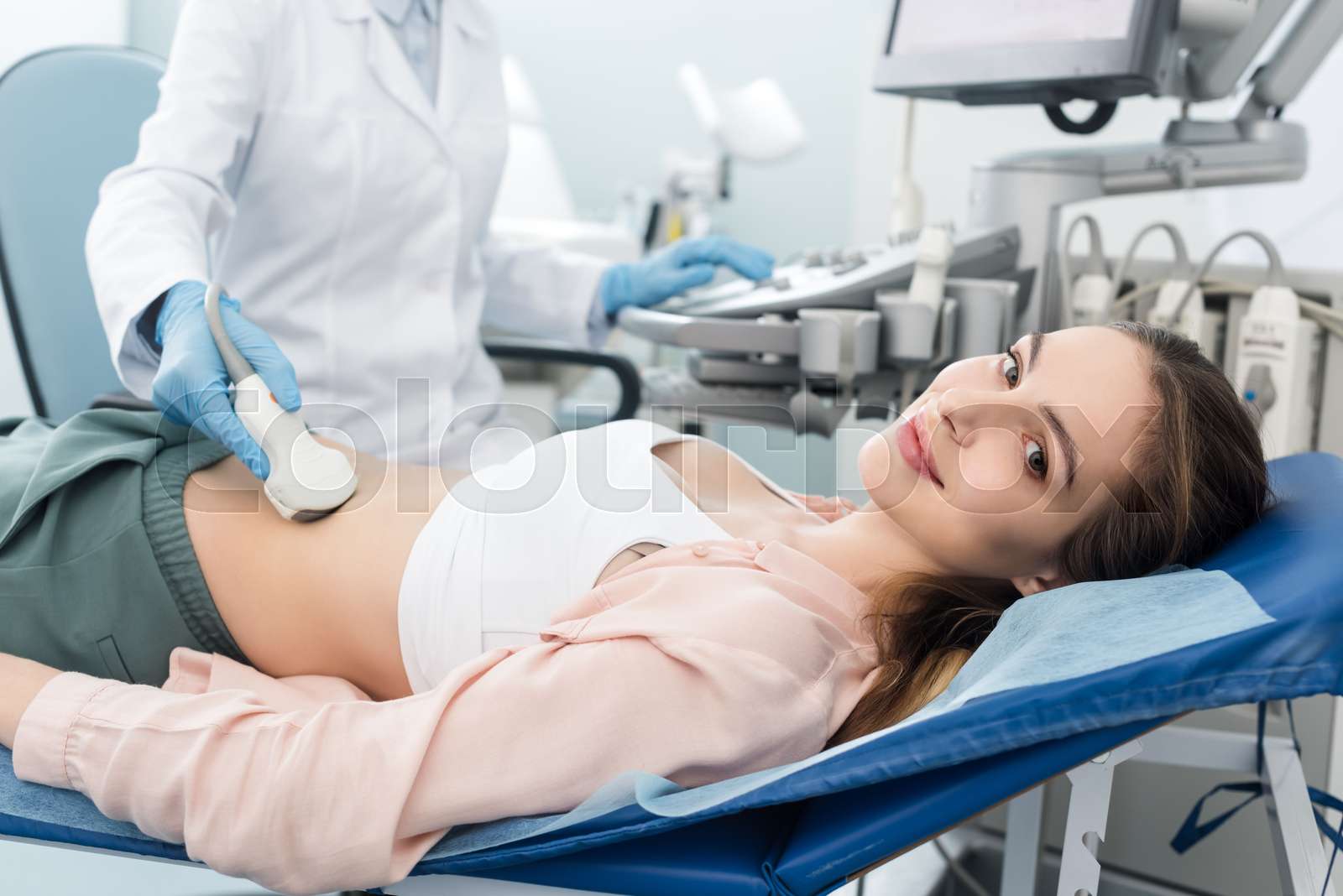 Doctor Examining Stomach Of Beautiful Patient With Ultrasound Scan In