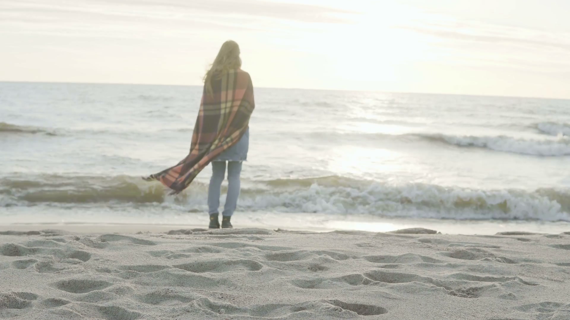 Back View Of The Young Woman Standing On Shore Of Sea And Looking Into