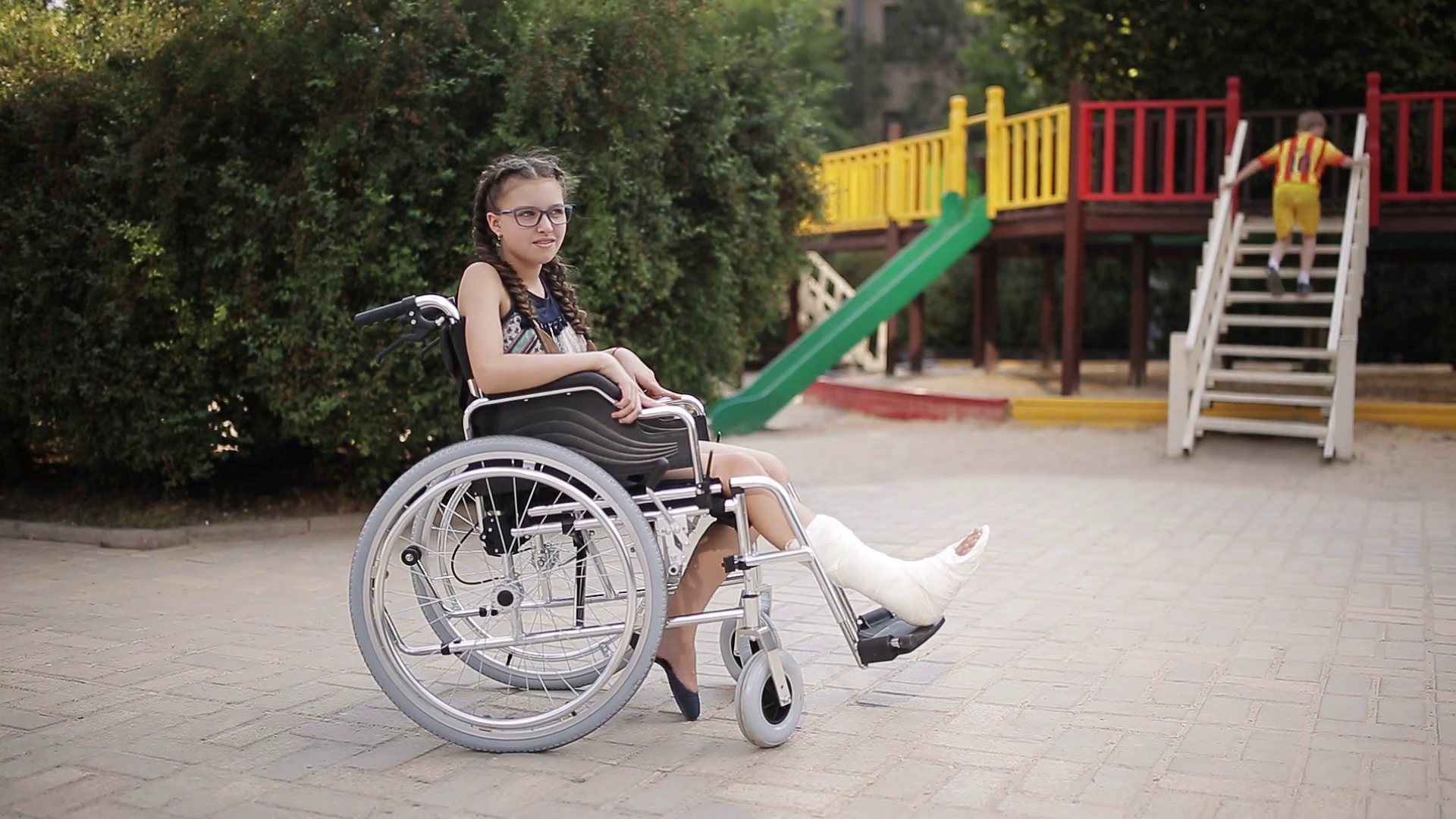 A Girl With A Broken Leg Sits In A Wheelchair In Front Of The