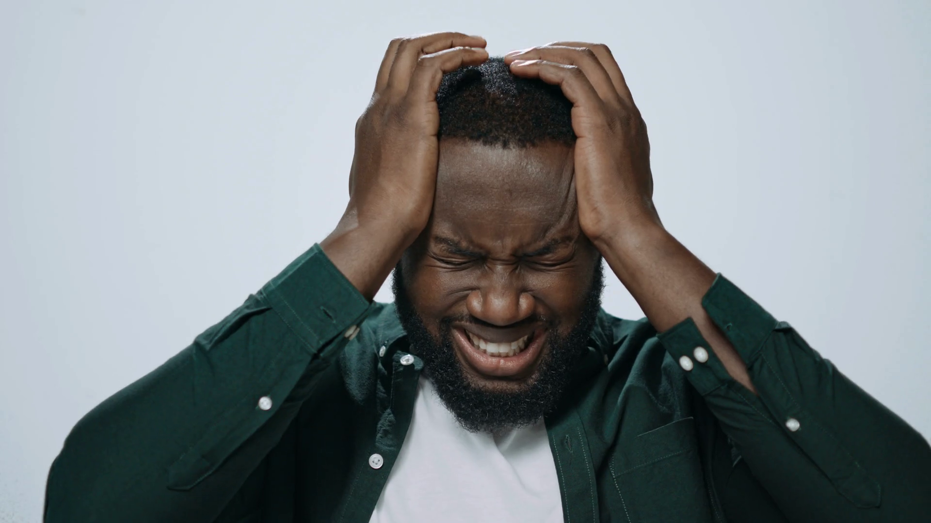 Portrait Of Exhausted African Man Holding Hands On Head At Grey