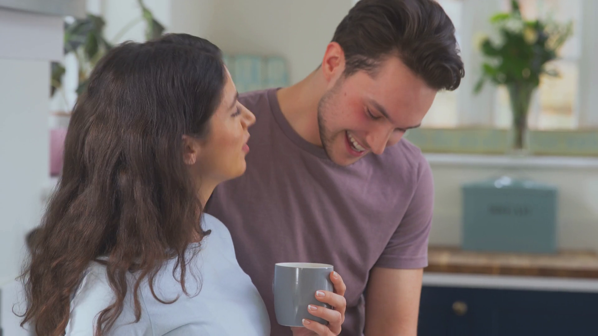 Pregnant Transgender Couple At Home In Kitchen Relaxing With Coffee As