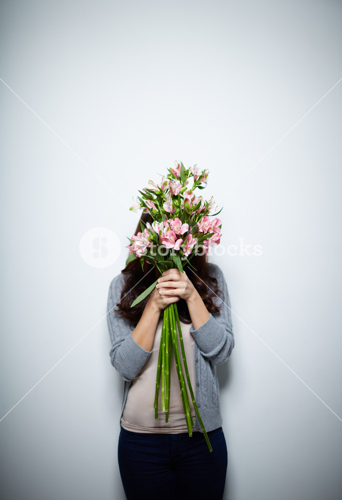 Portrait Of Young Female Hiding Her Face Behind Bunch Of Fresh Flowers