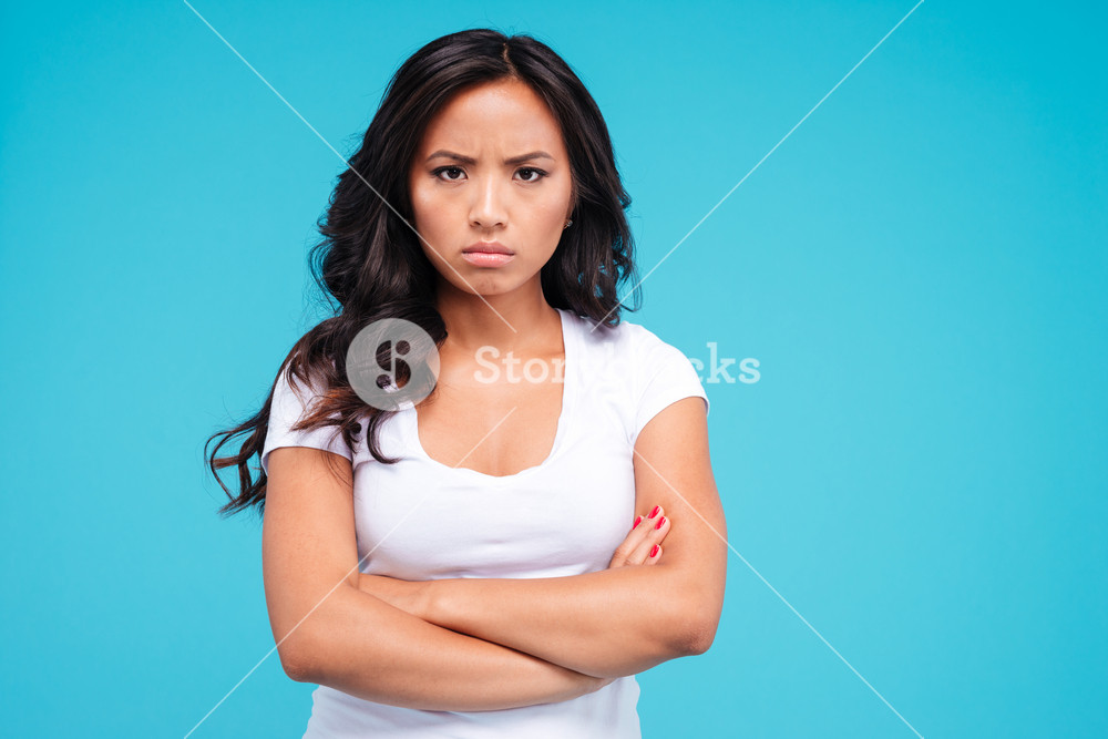 Assertive Woman Standing With Arms Crossed On Blue Background Royalty