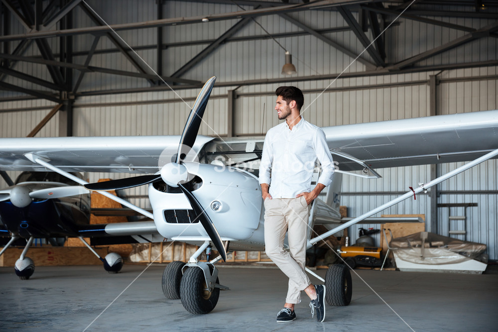 Full Length Of Smiling Young Man Standing Near Small Aircraft Royalty