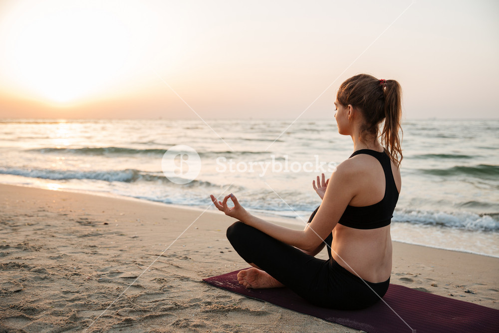 Young Woman Meditating On The Beach At Sunset Royalty Free Stock Image