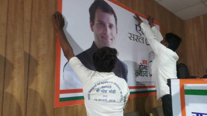 Worker Putting Up Rahul Gandhis Posters While Wearing A Modi T Shirt